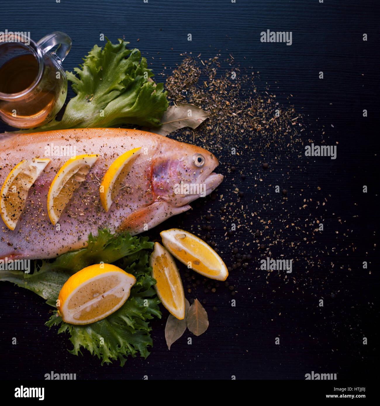 Fresh trout and ingredients to prepare fish dishes on black table Stock ...