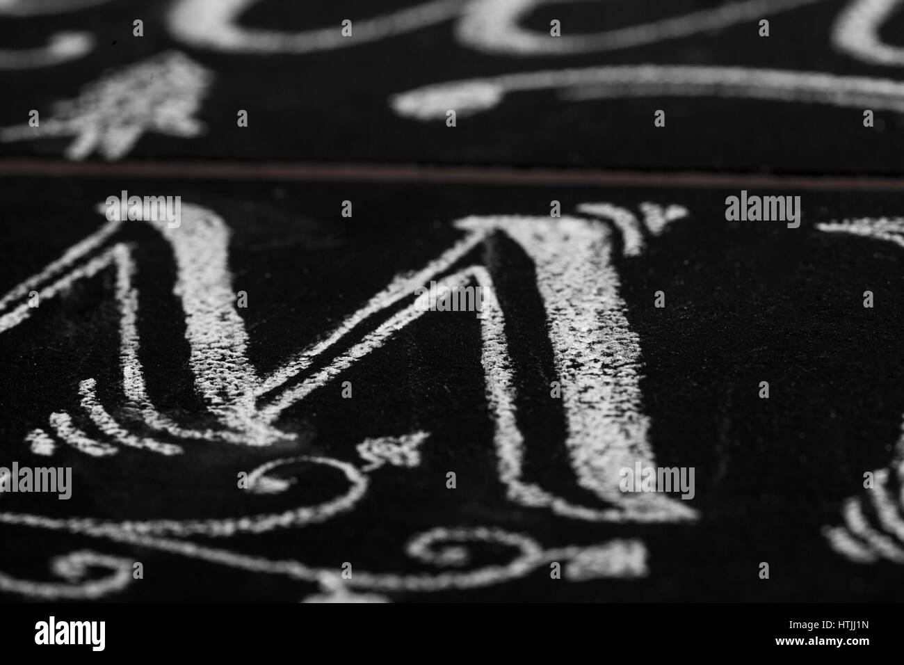 Closeup of calligraphy letter M drawn with chalk. Shallow depth of ...