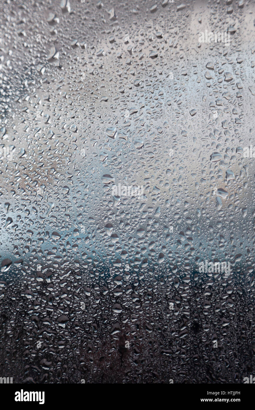 vertical pivcture of rain drops on windshield of car and background in ...