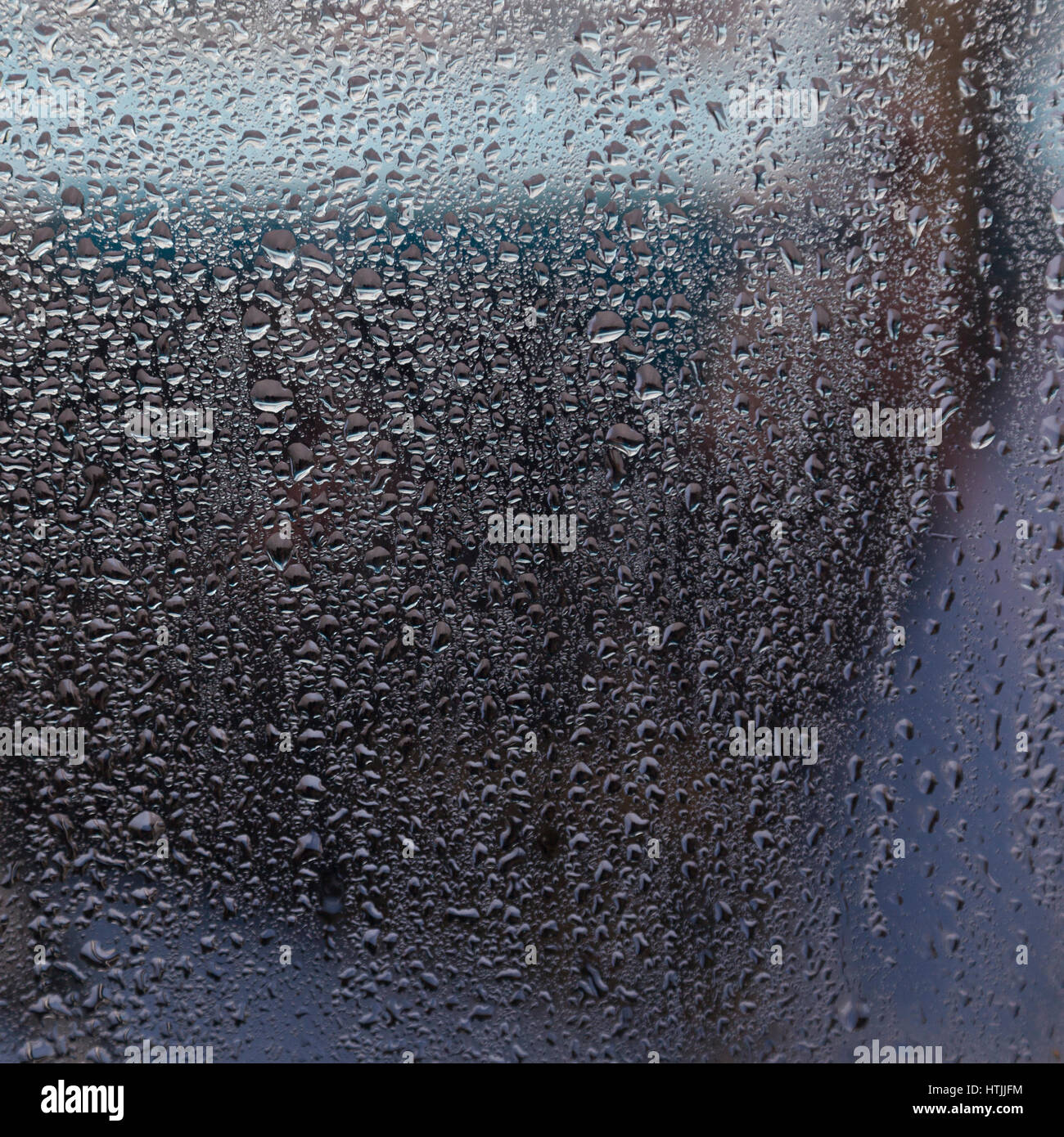 square picture of rain drops on windshield of car and background in ...
