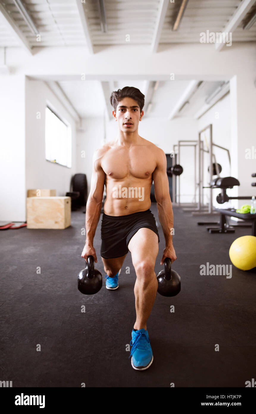 Fit hispanic man doing strength training, doing lunges with kettlebells ...