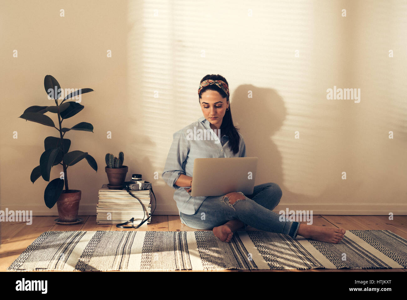 Attractive trendy young woman working on a laptop computer as she sits ...