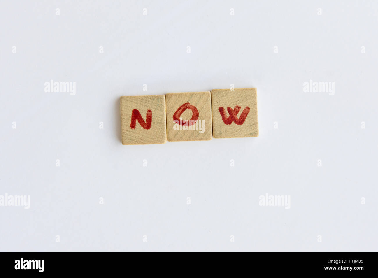 the word Now formed with letters written on squares of wood dowels ...