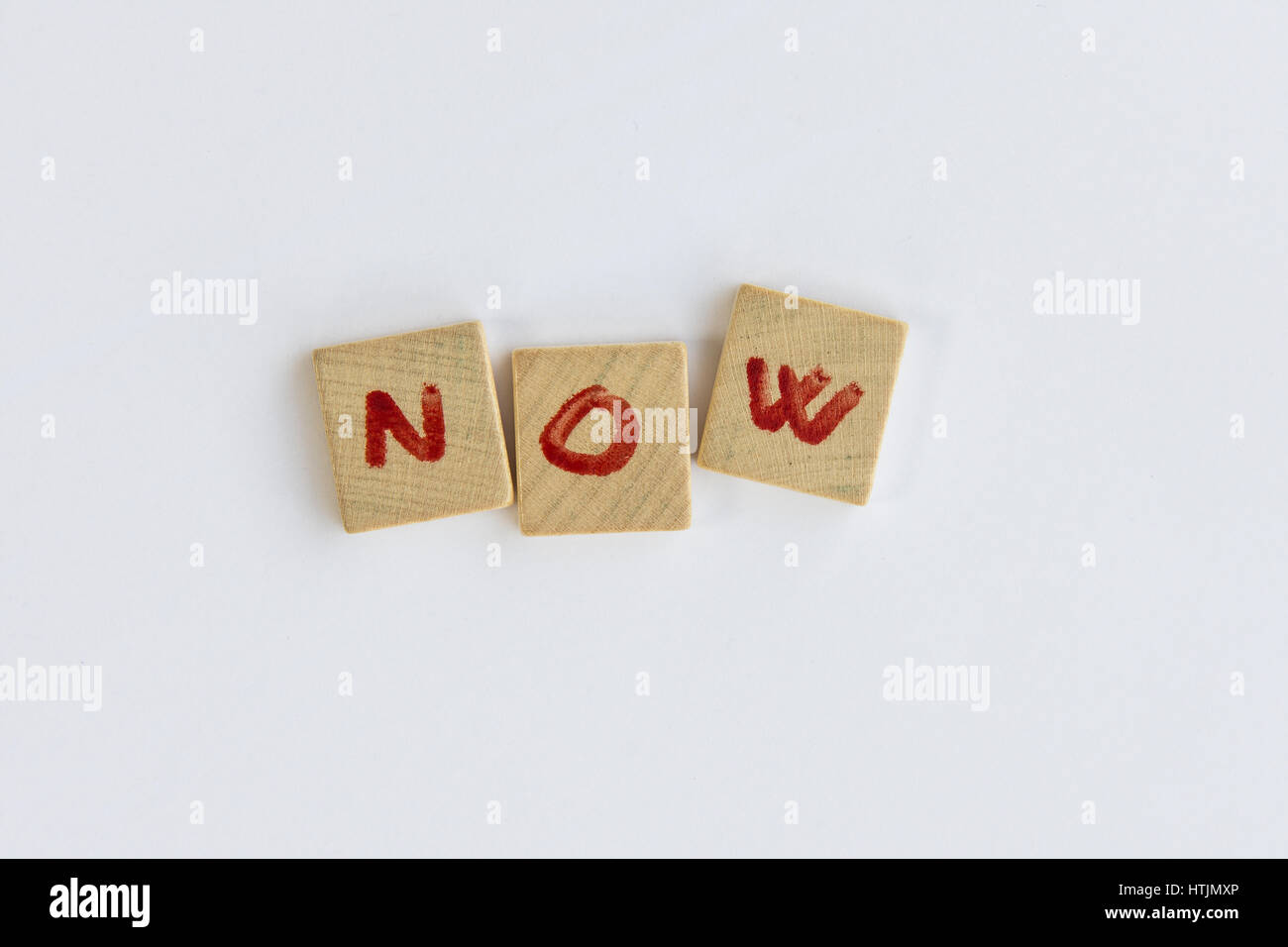 the word Now formed with letters written on squares of wood dowels ...