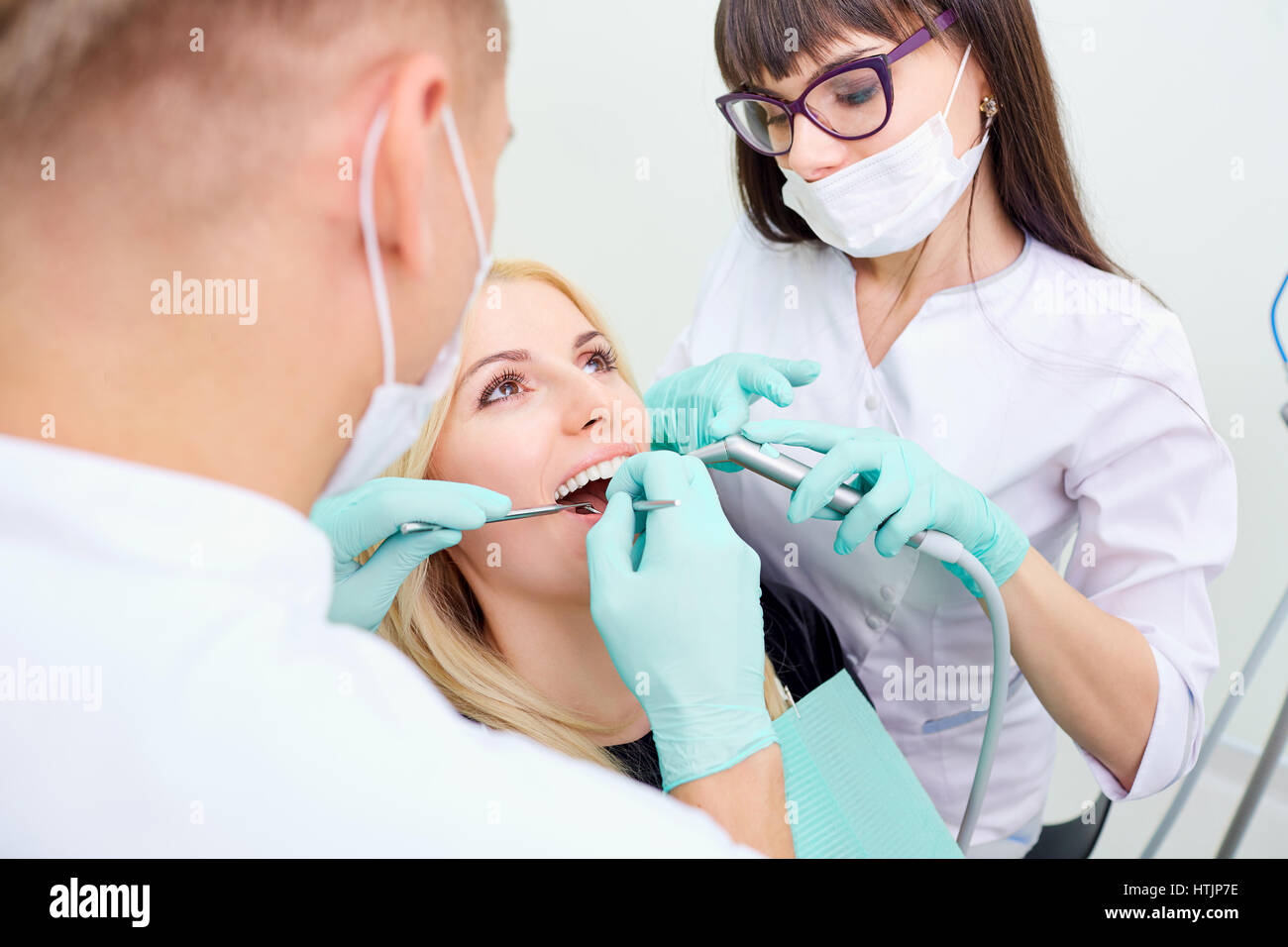The dentist man and assistant woman are treating teeth to client in ...
