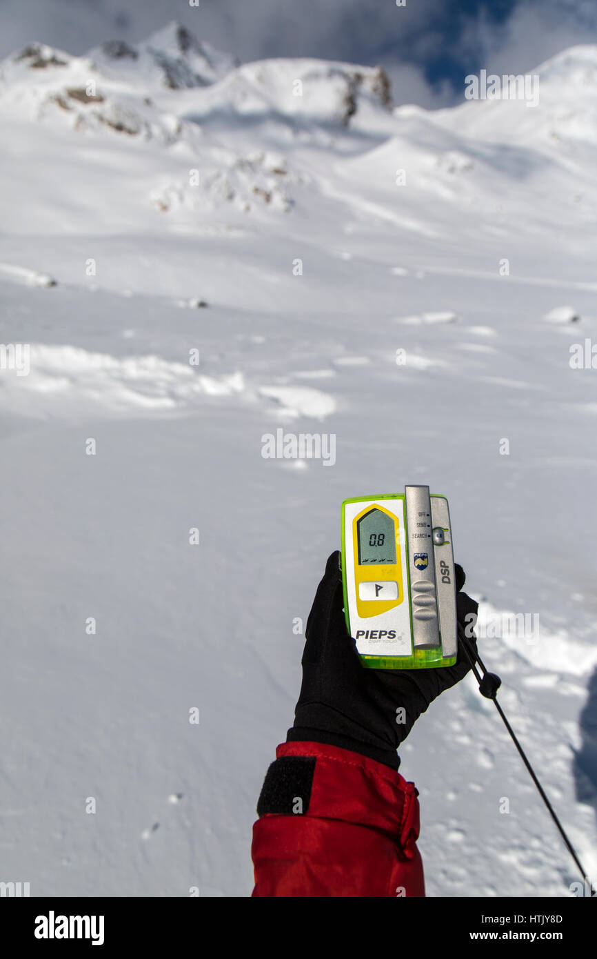 Person using a Pieps avalanche transceiver in snowy mountains. Close up ...