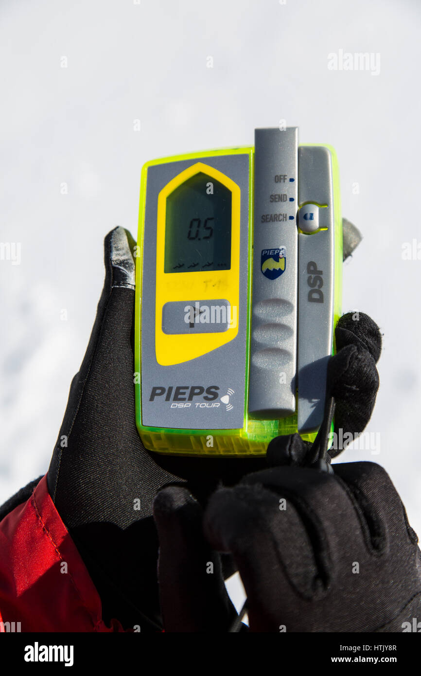 Person using a Pieps avalanche transceiver in snowy mountains. Close up ...