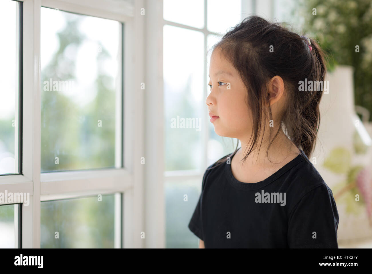 Lonely Asian child looking out window expressing her emotion Stock ...