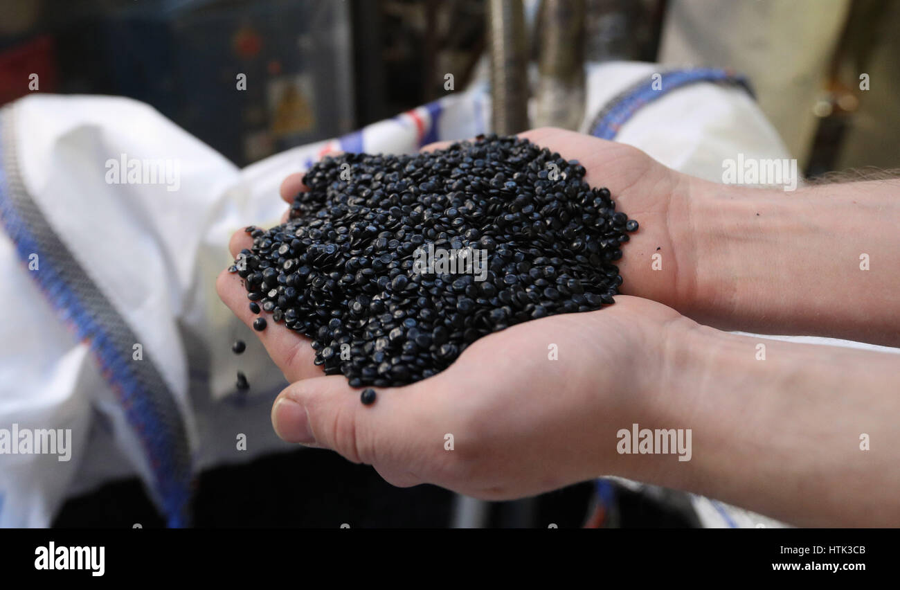 A press room operative grabs a handful of black pvc pellets at the ...