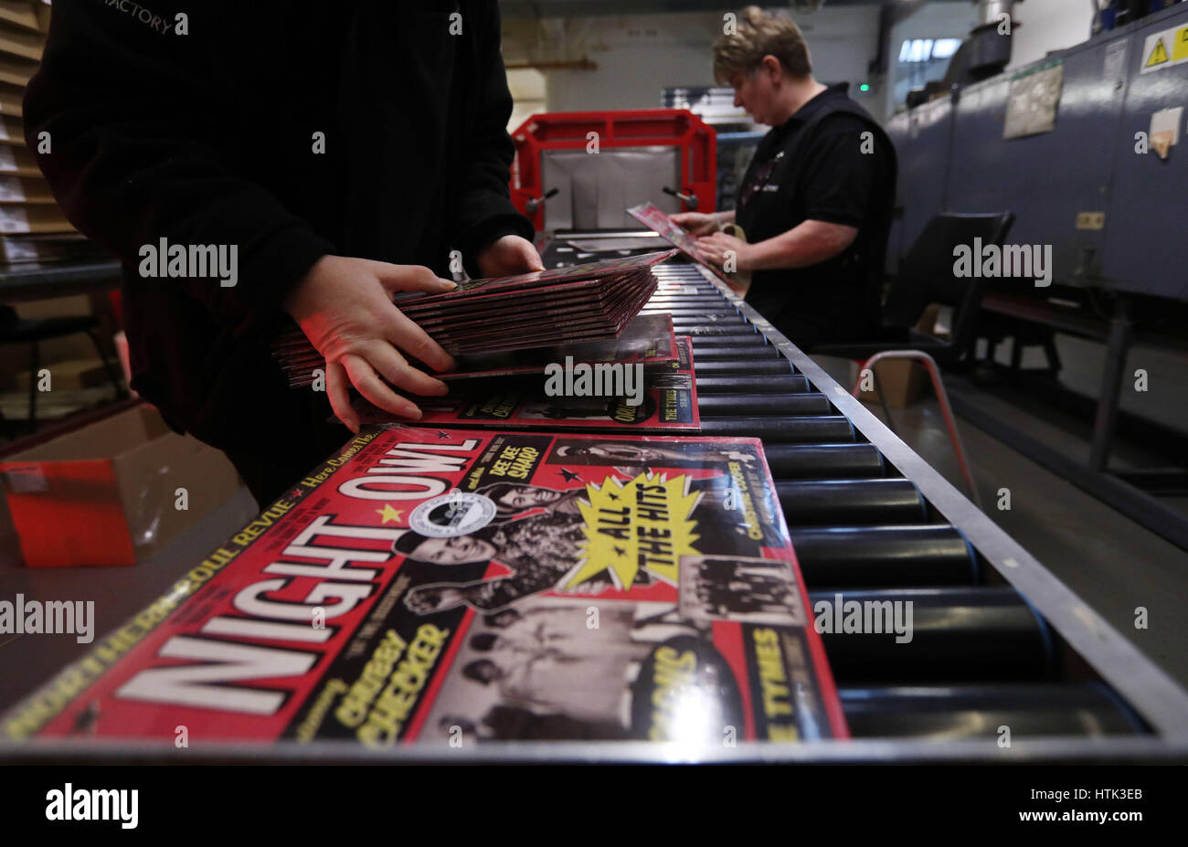 Packing operatives apply stickers to vinyl records in their sleeves ...