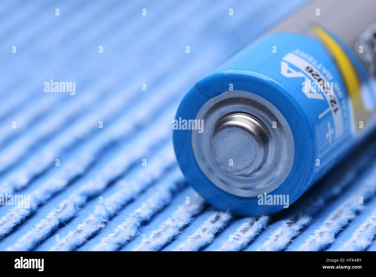 Single AA Battery Closeup Lying on Blue Background Stock Photo - Alamy