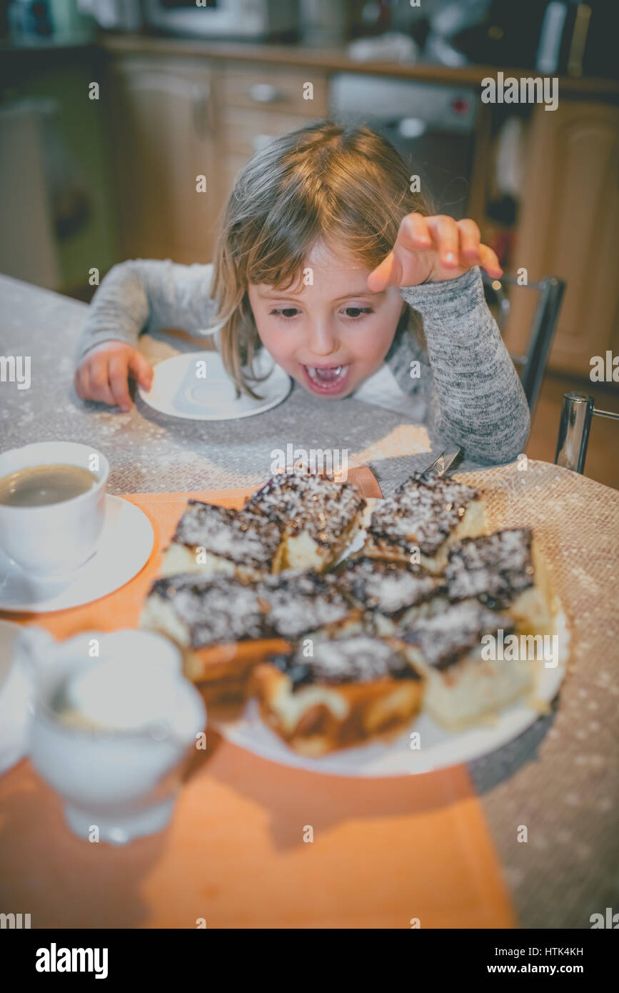 Portrait of a cute little girl that is about to grab and devour a piece ...