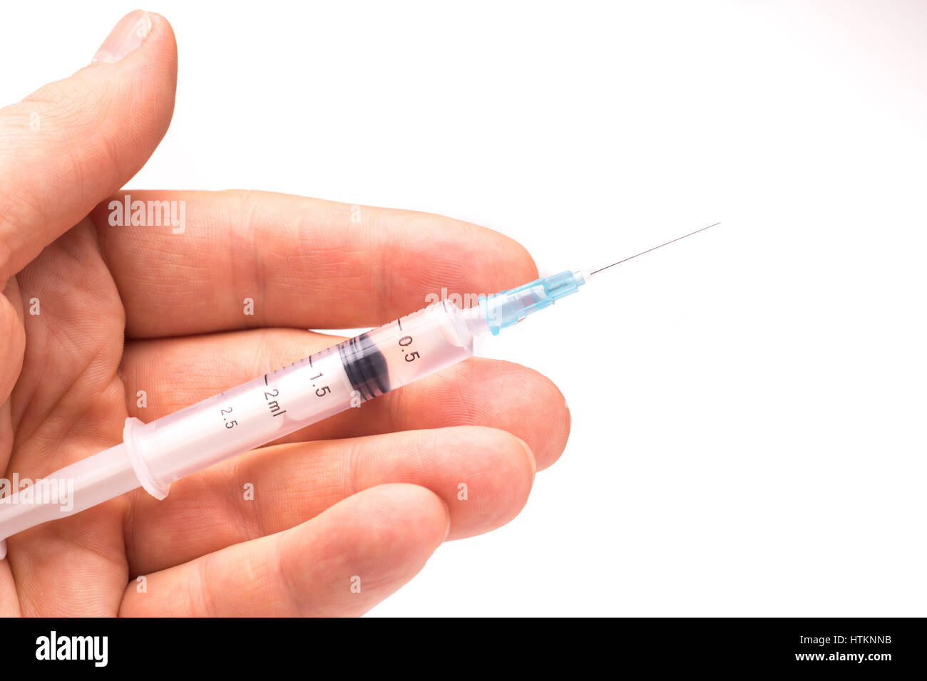 Hand holding a syringe, the syringe is filled with clear liquid and the ...