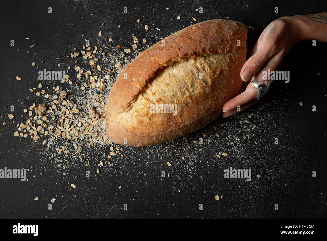 Human hand holding fresh bread on a black background Stock Photo - Alamy