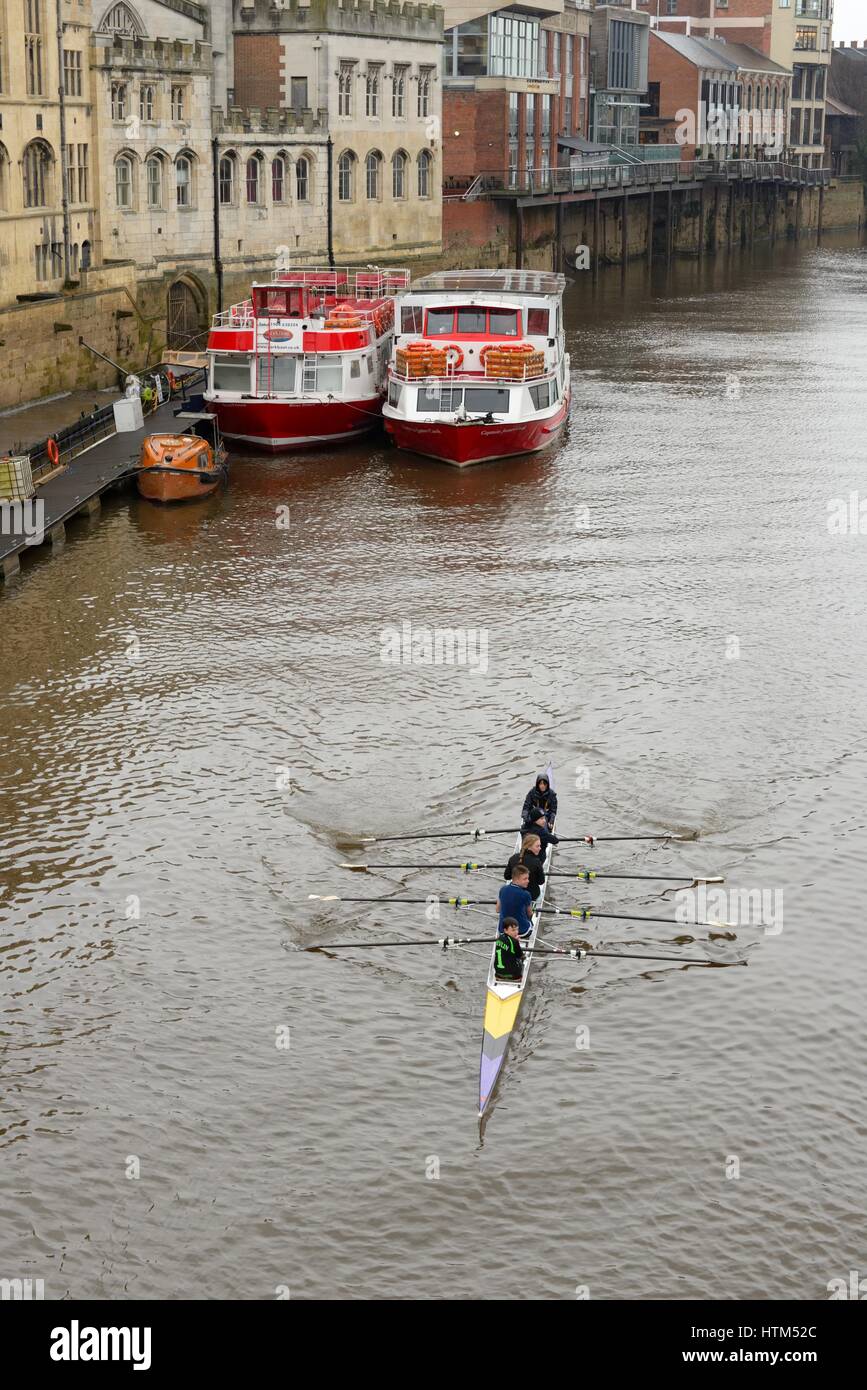 Teenagers rowing on the River Ouse through the city of York in England ...