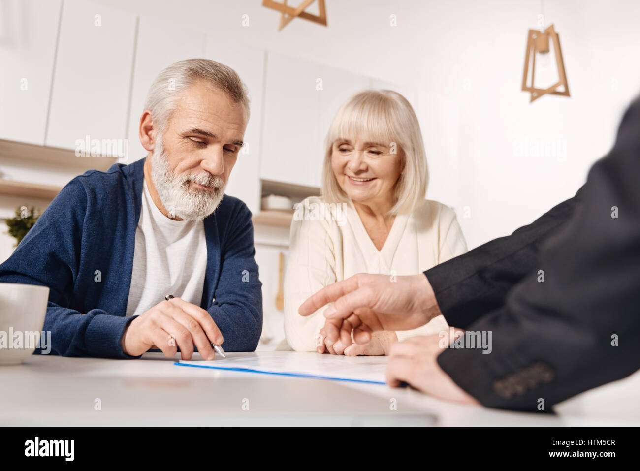 Resolute elderly couple signing agreement at home Stock Photo - Alamy
