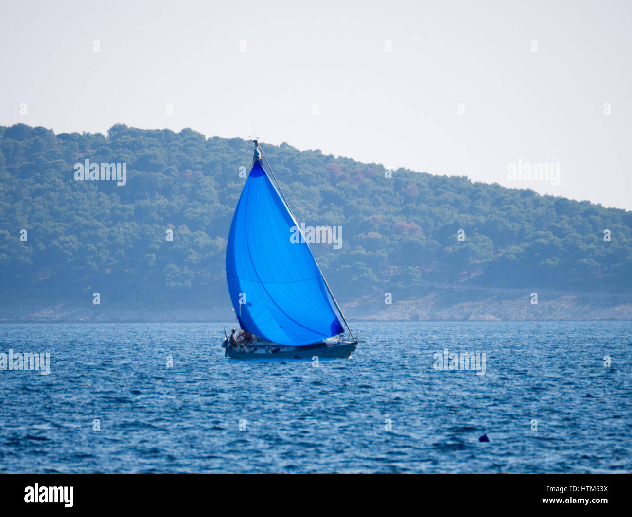 a yacht sailboat boat with blue sail sails sailing on the sea ocean ...