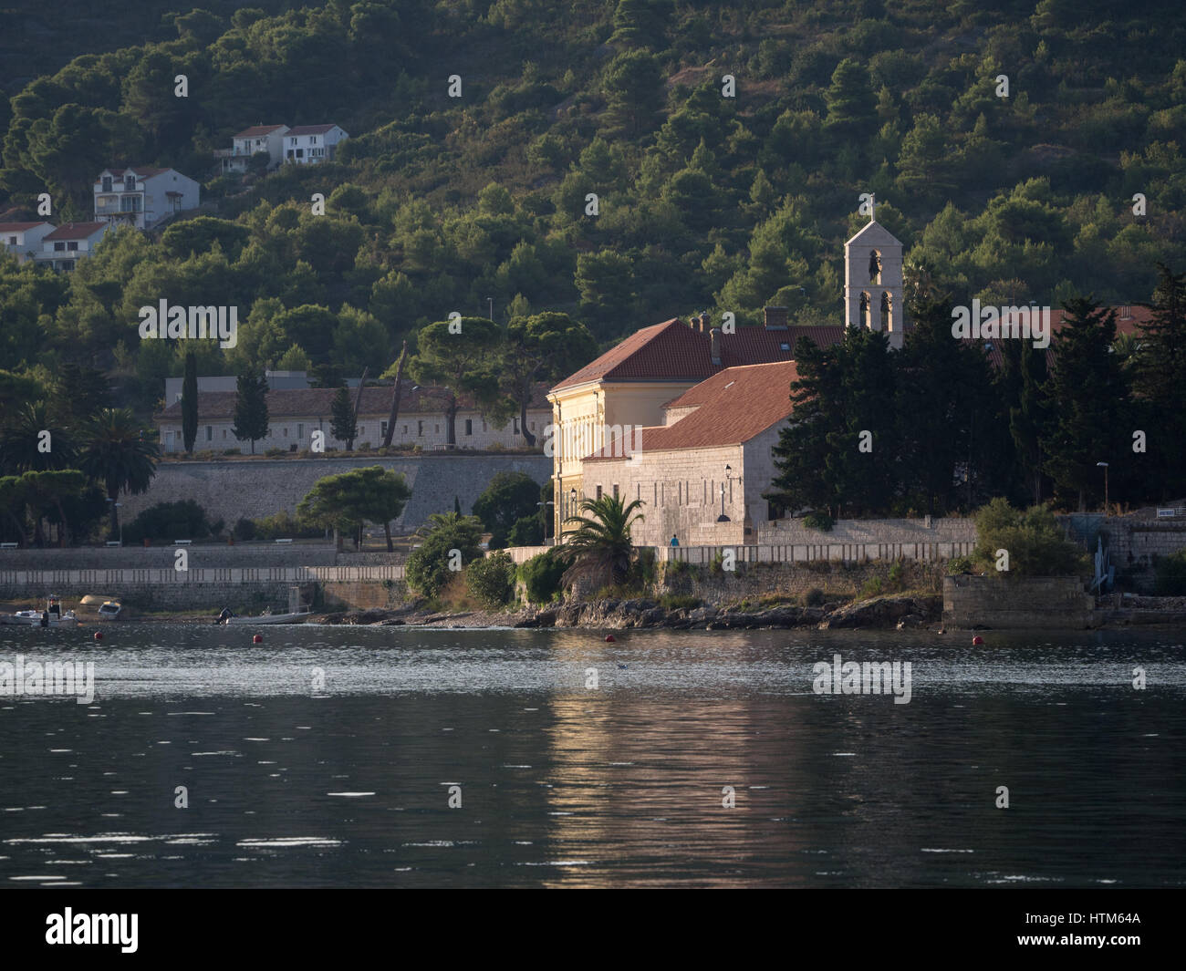 dawn light shining on a church by calm water in Vis harbor harbour ...