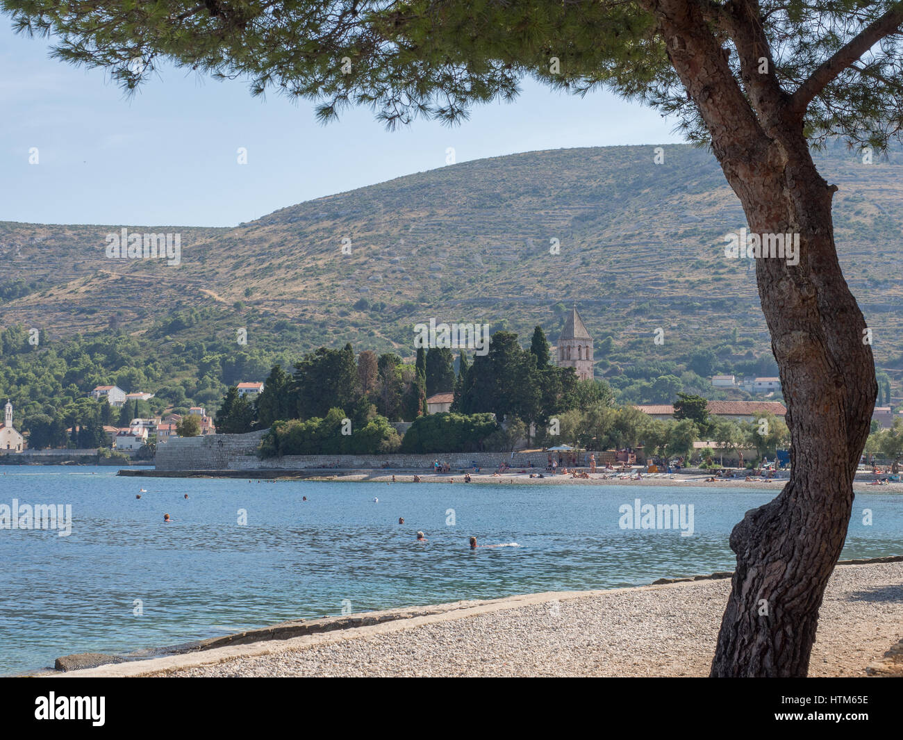 an island in middle of Vis harbour harbor from beach with swimmers in ...