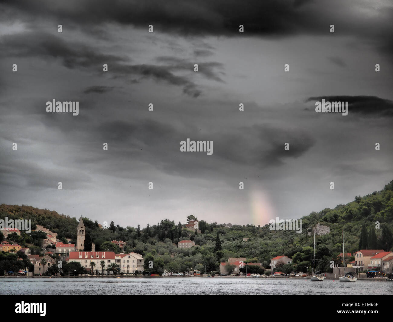 An angry stormy storm dark sky with clouds and a rainbow above town ...
