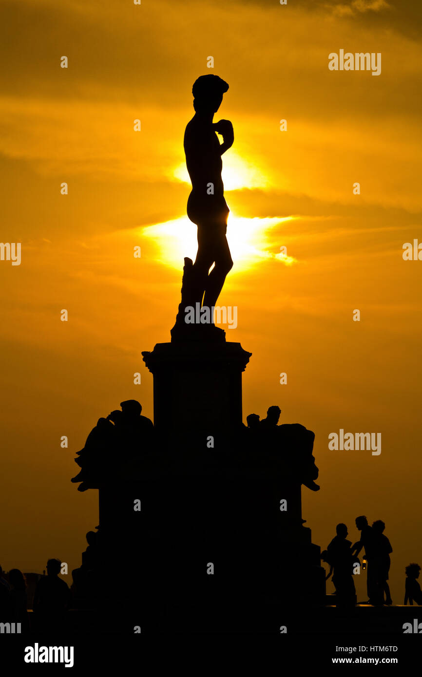Classical roman figural statue of a young man on a plinth silhouetted ...