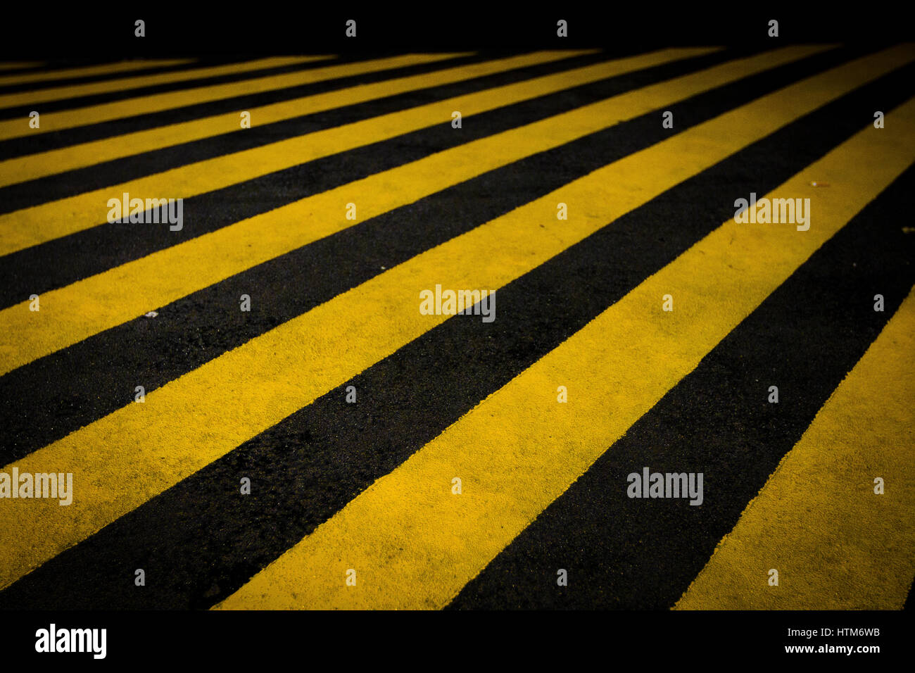 Diagonal yellow stripes of crosswalk on black background, close-up full ...