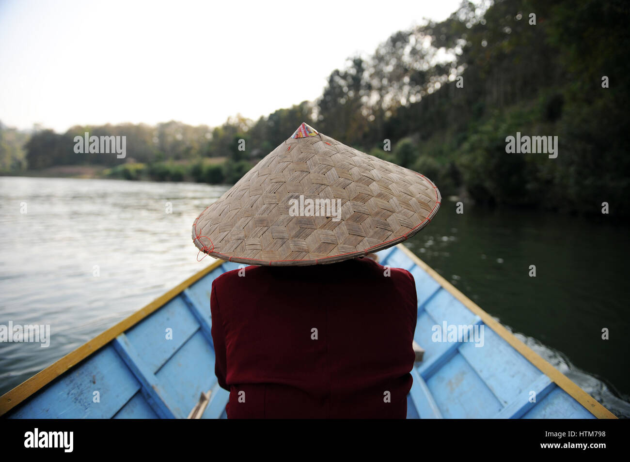 Woman on a boat is wearing an Asian conical hat in Laos. The shape of ...