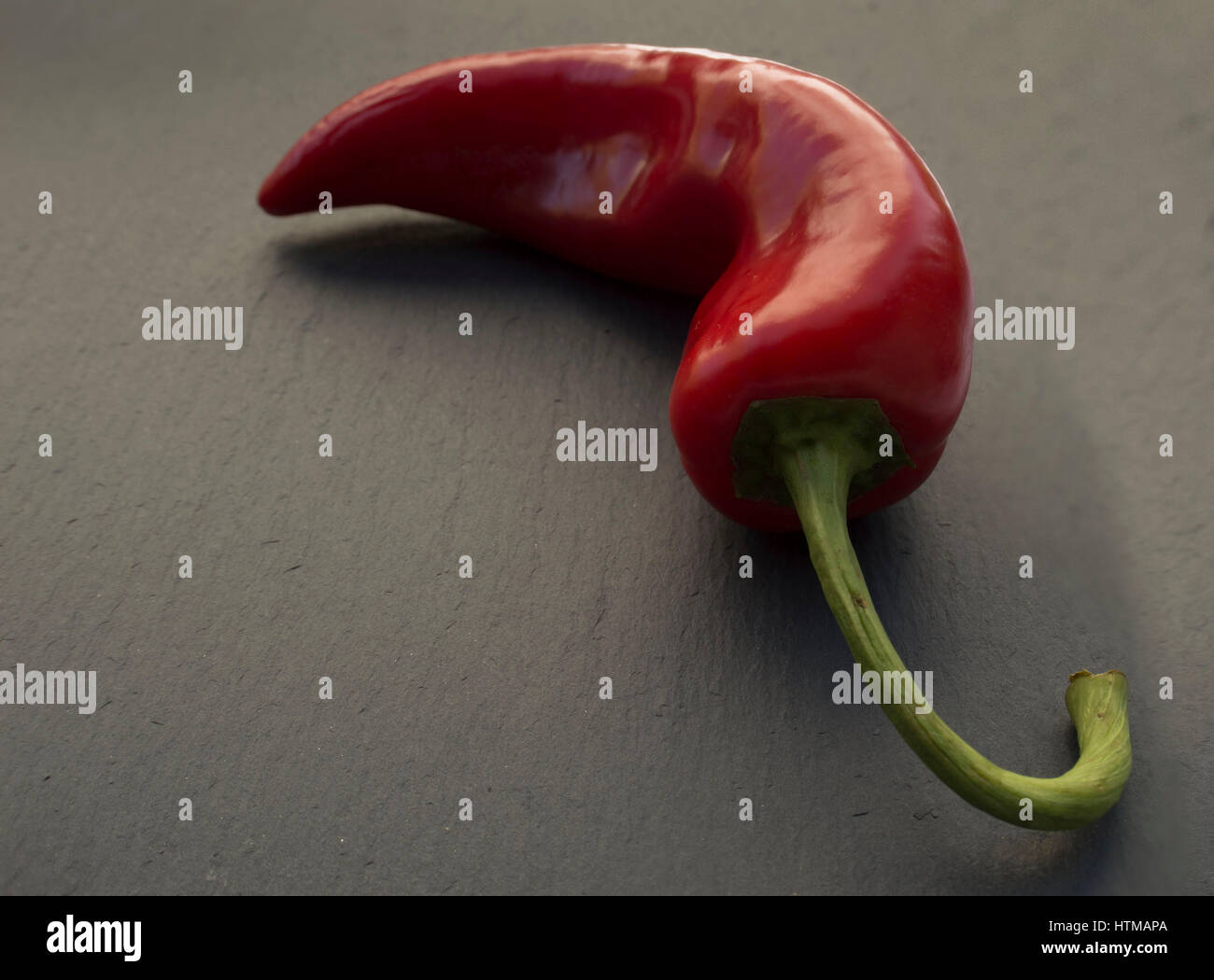 single red bell pepper on black slate Stock Photo - Alamy