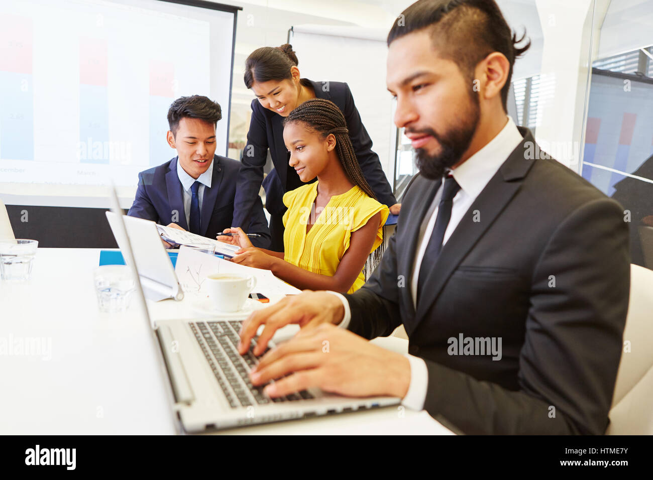 Businessman taking notes and writing with computer in team meeting ...