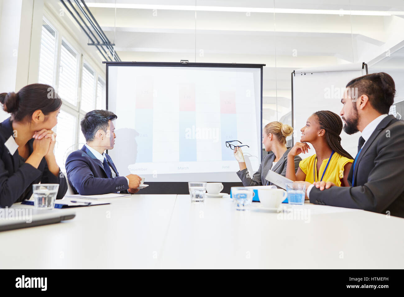 Businesspeople analyzing statistics flipchart in business meeting ...