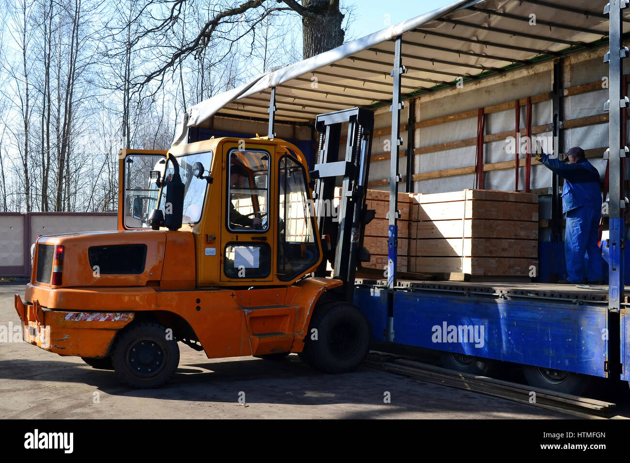 yellow front-end loader loads the Packed boards in a trailer truck ...