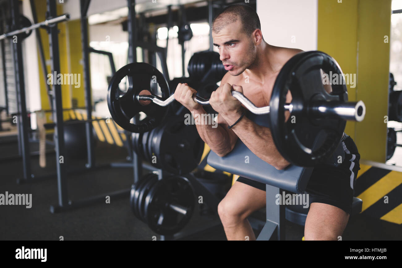 Determined male working out in gym lifting weights Stock Photo - Alamy