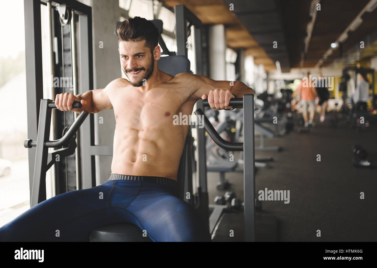 Determined muscular man exercising and working out in gym Stock Photo ...