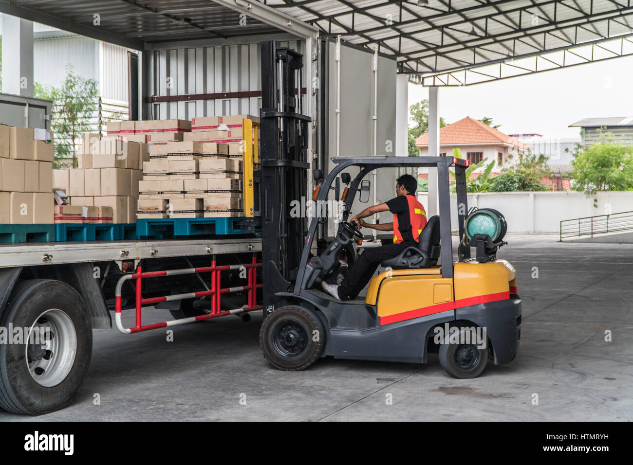 Worker loading pallet with a forklift into a truck Stock Photo - Alamy