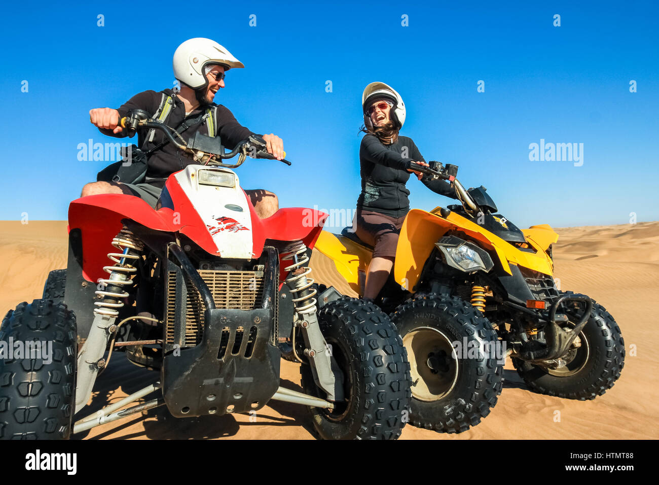 Quad driving people - happy smiling couple bikers in sand desert Stock ...
