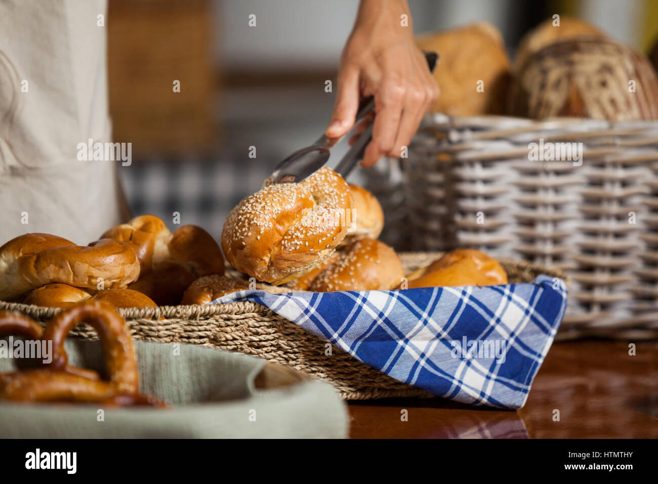 Mid-section of staff holding bread with tong in bakery shop Stock Photo ...
