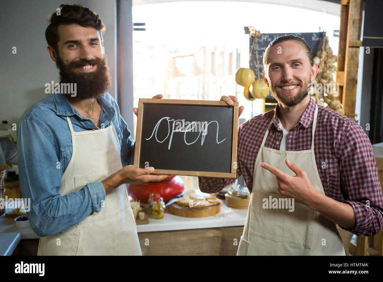 Smiling male staffs holding a open sign in market Stock Photo - Alamy