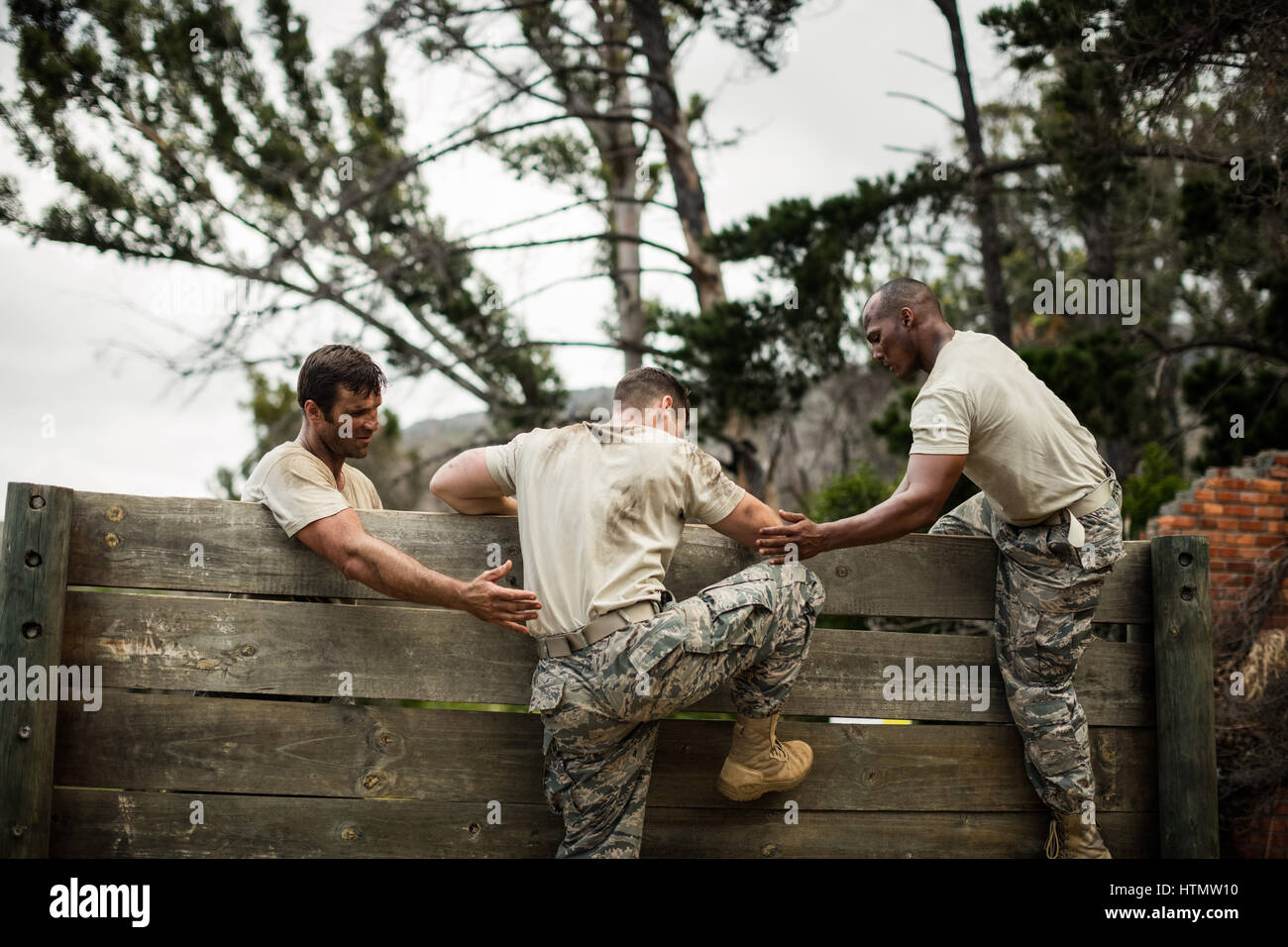 Soldiers helping man to climb wooden wall in boot camp Stock Photo - Alamy
