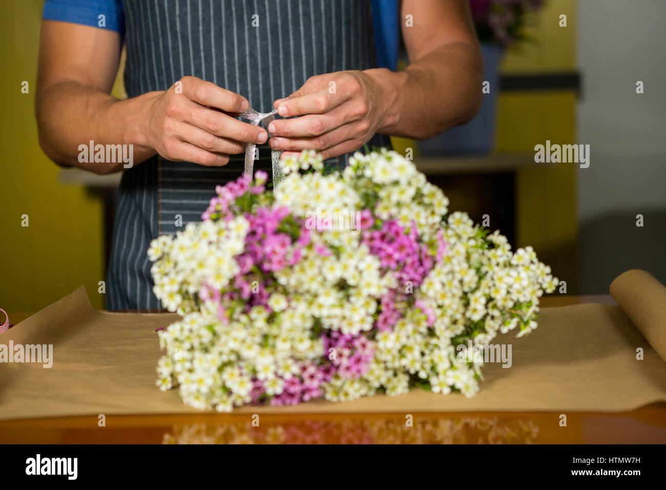 Mid section of male florist preparing a flower bouquet in flower shop ...