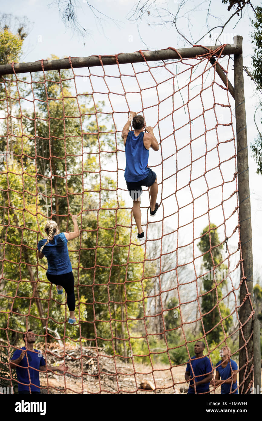 People climbing a net during obstacle course in boot camp Stock Photo ...