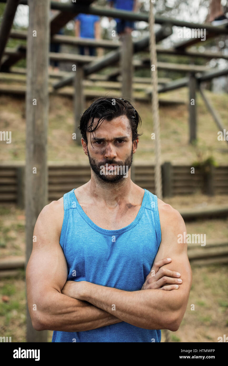 Portrait of determined man standing with arms crossed in boot camp ...