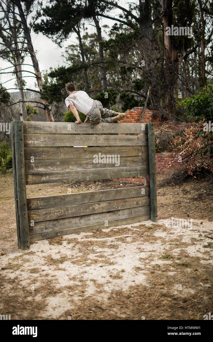 Rear view of soldier climbing wooden wall in boot camp Stock Photo - Alamy