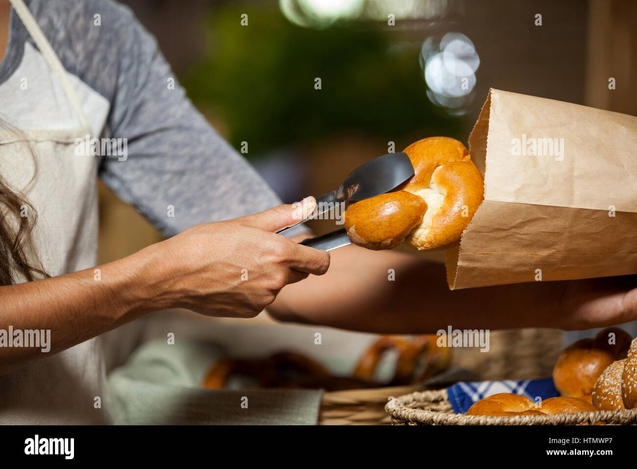 Mid-section of staff packing bread in paper bag at bakery shop Stock ...