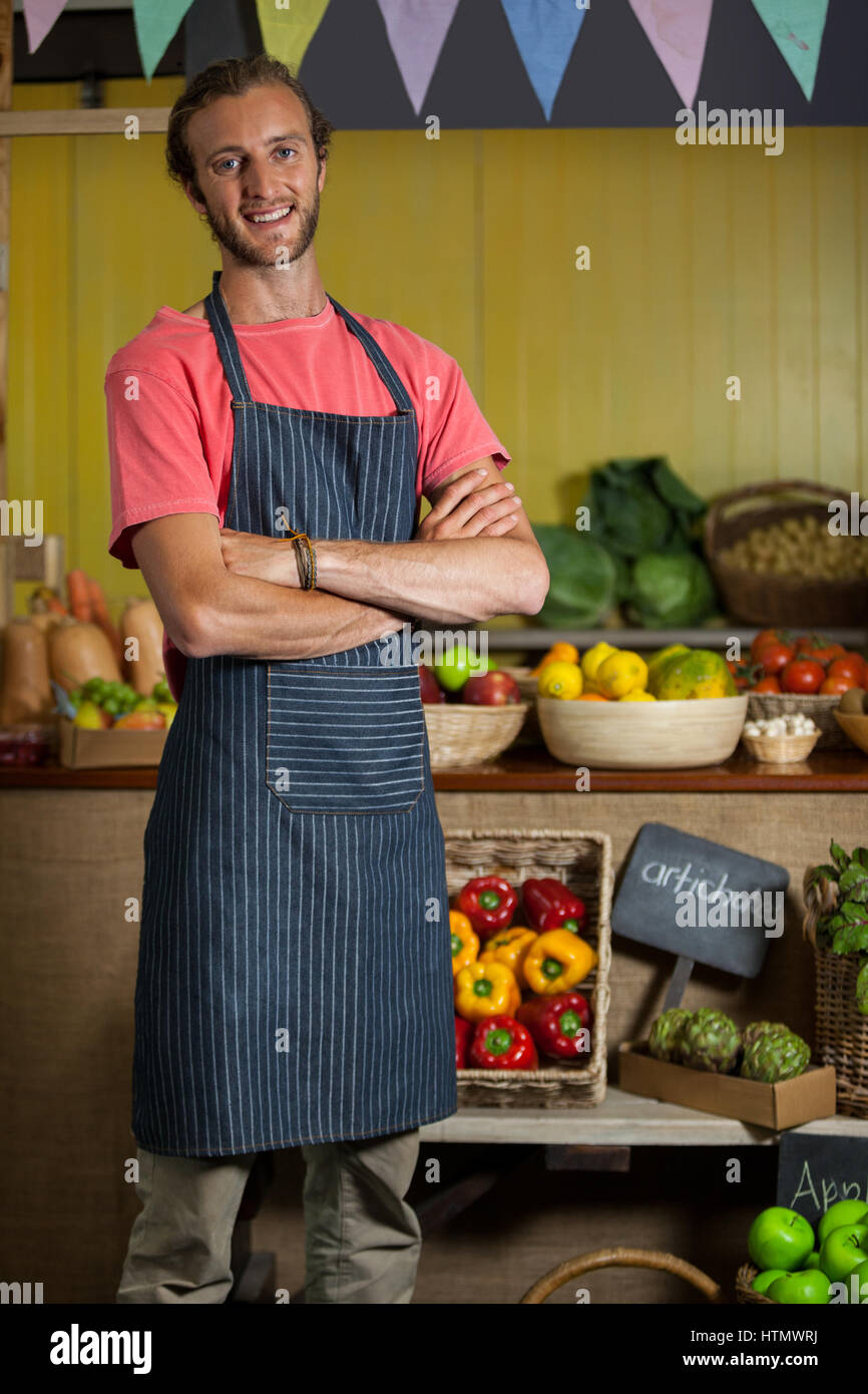 Portrait of male staff standing with arms crossed in organic section of ...