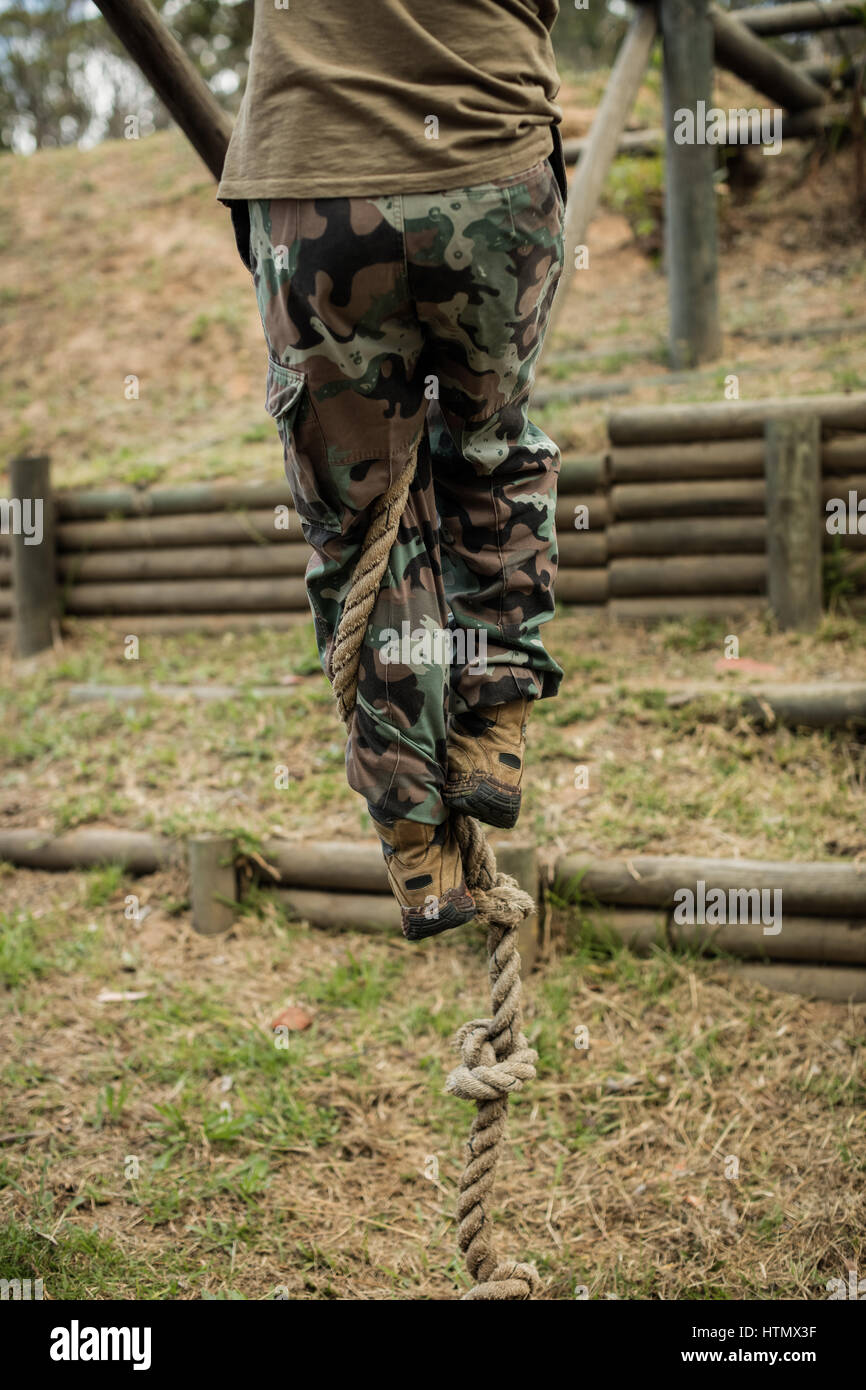 Low section of man climbing a rope during obstacle course in boot camp ...