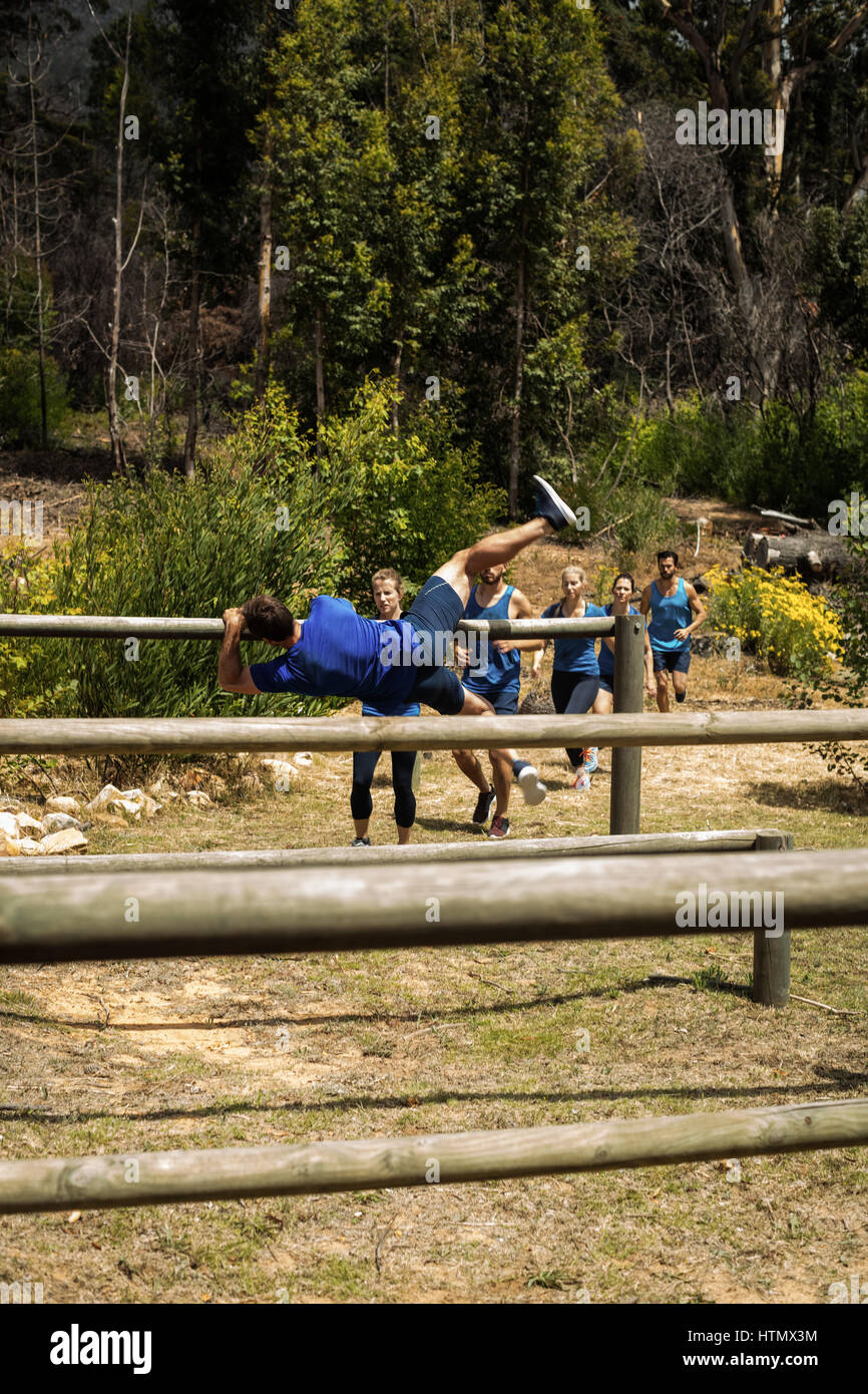 People jumping over the hurdles during obstacle course in boot camp ...