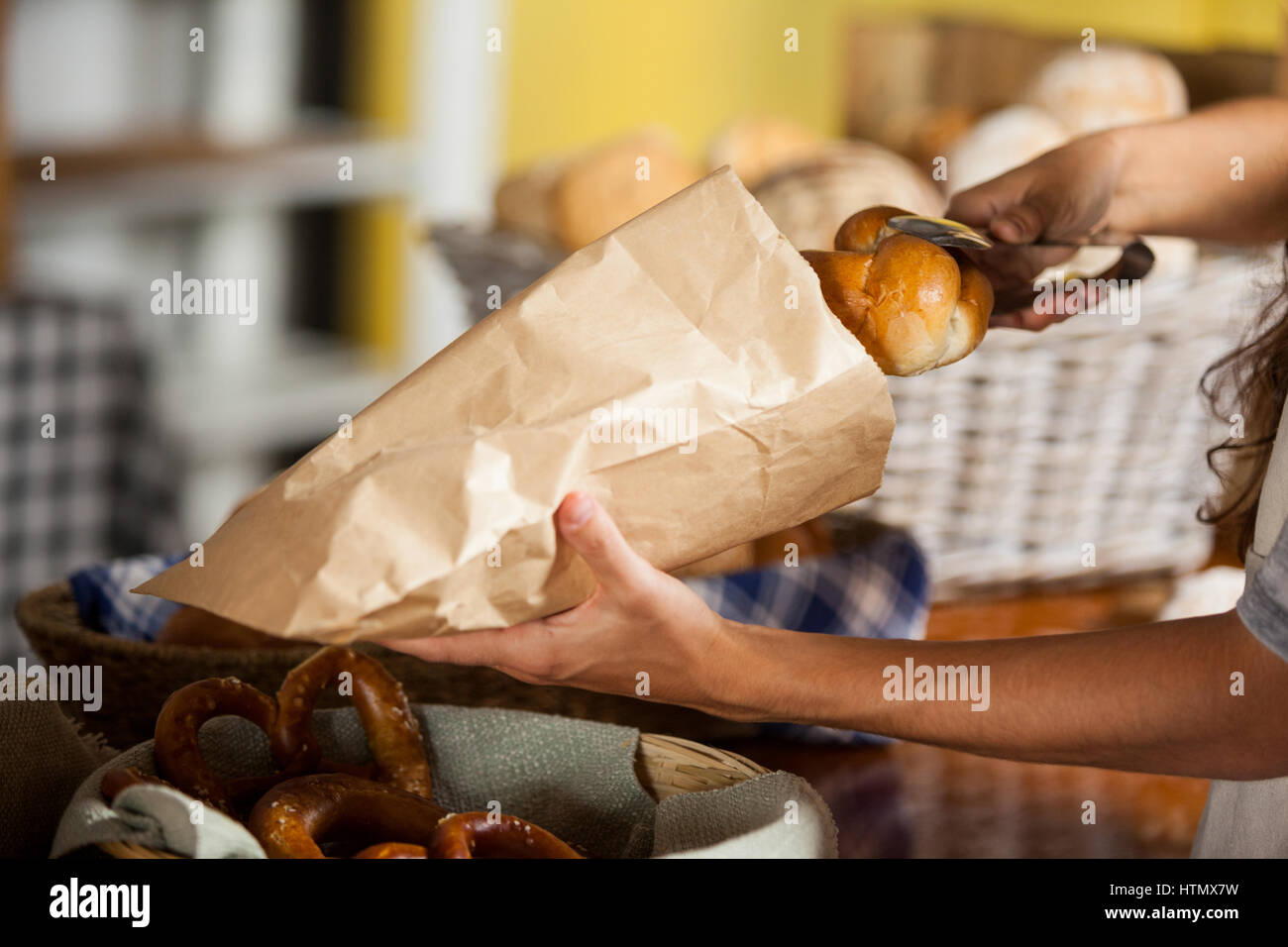 Mid-section of staff packing bread in paper bag at bakery shop Stock ...