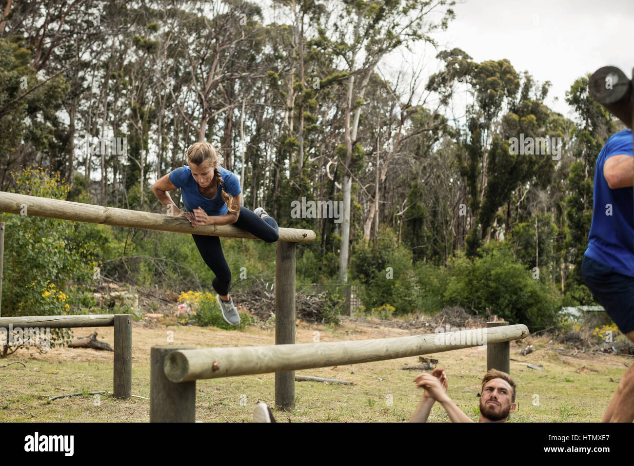 Woman jumping over the hurdles during obstacle course in boot camp ...