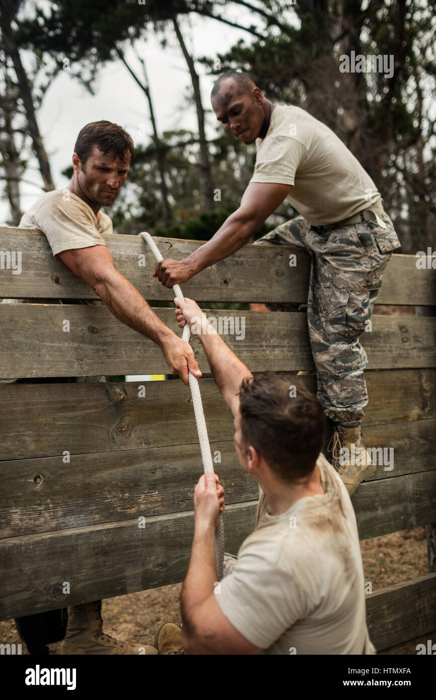 Soldiers climbing wooden wall with rope in boot camp Stock Photo - Alamy