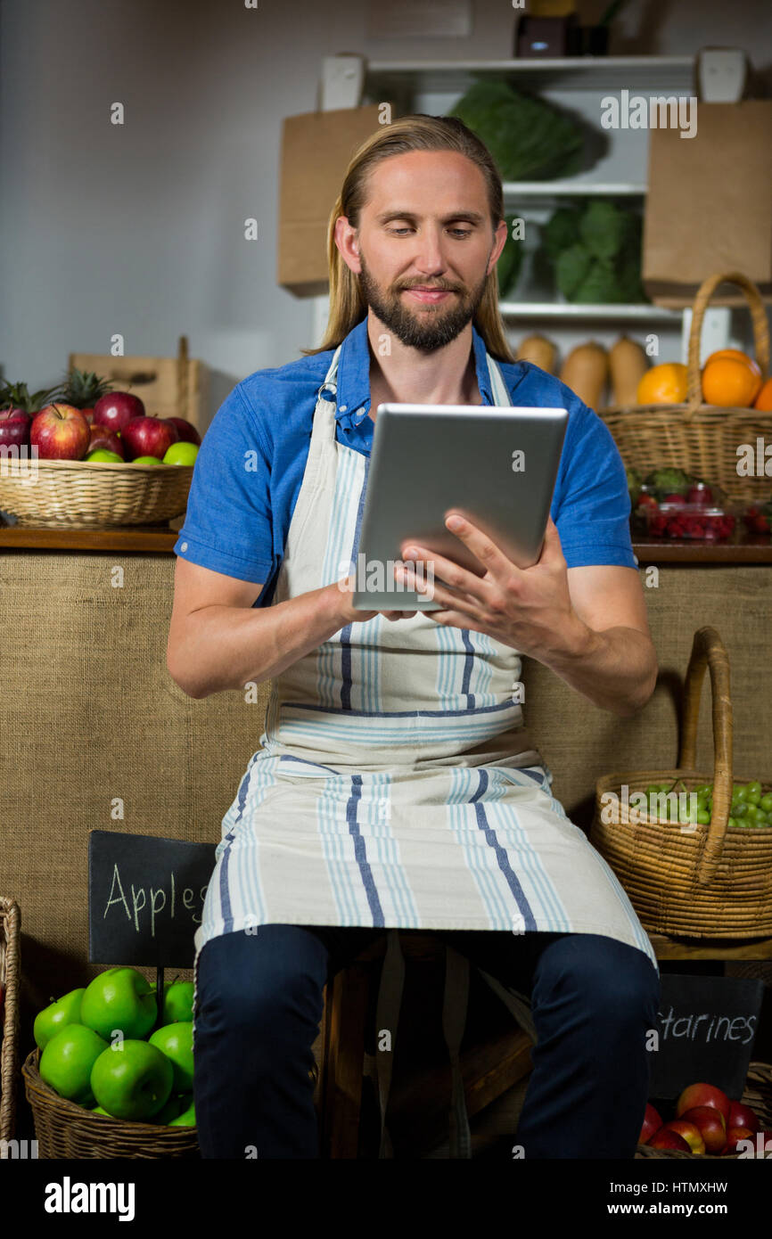 Smiling male staff using digital tablet at organic section in market ...